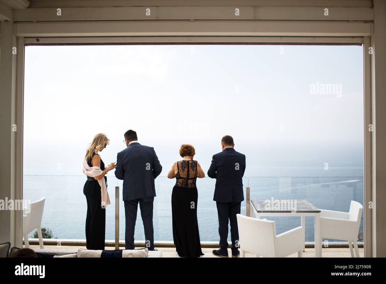 Four wedding guests talking on the balcony Stock Photo - Alamy