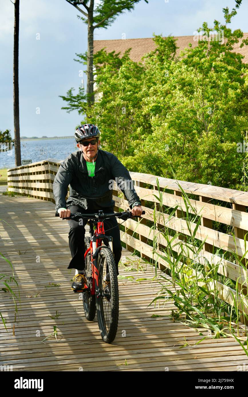 Middle aged, senior man pedaling a bicycle on scenic trails and ...