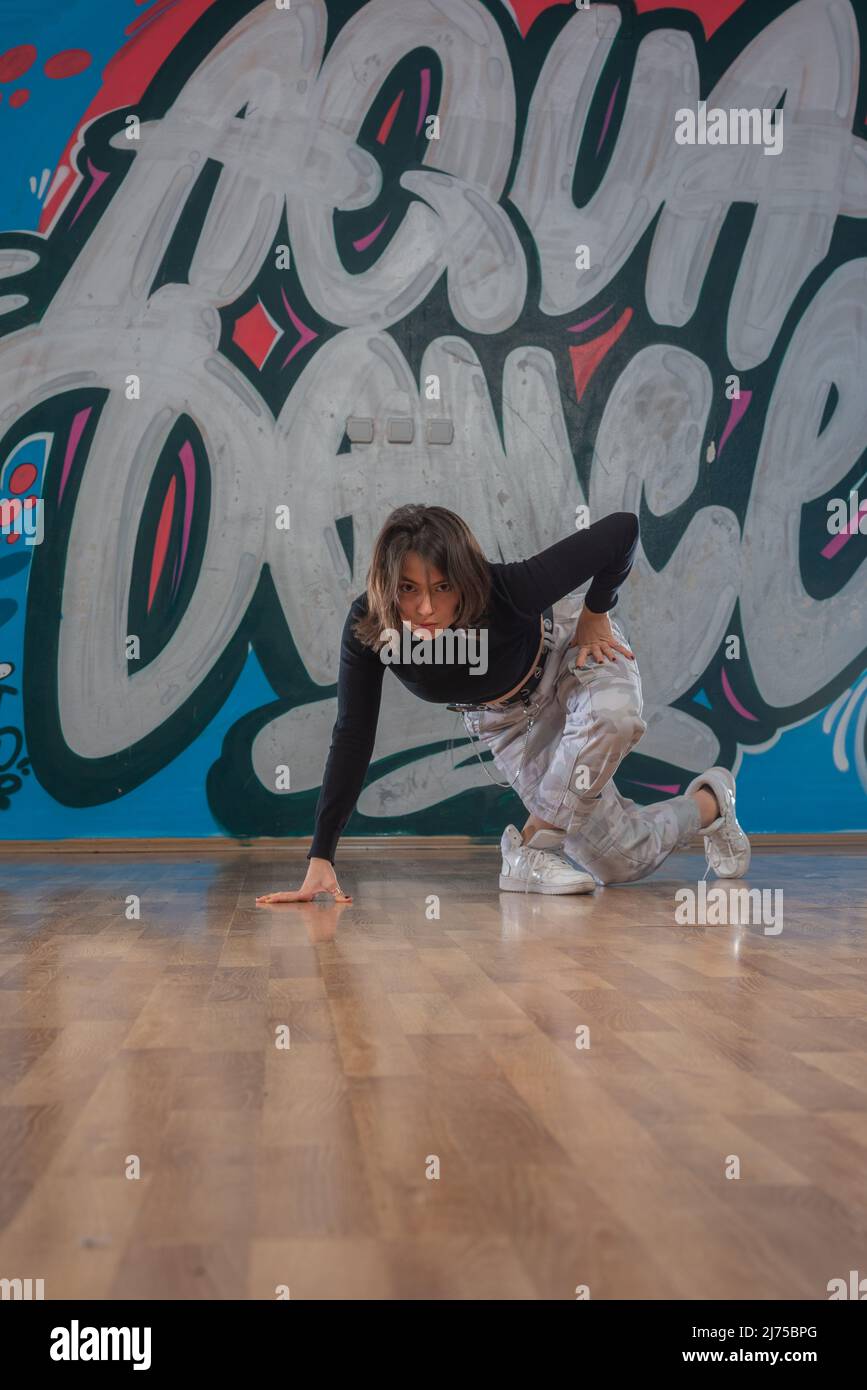 Attractive young woman doing breakdance move over graffiti background ...