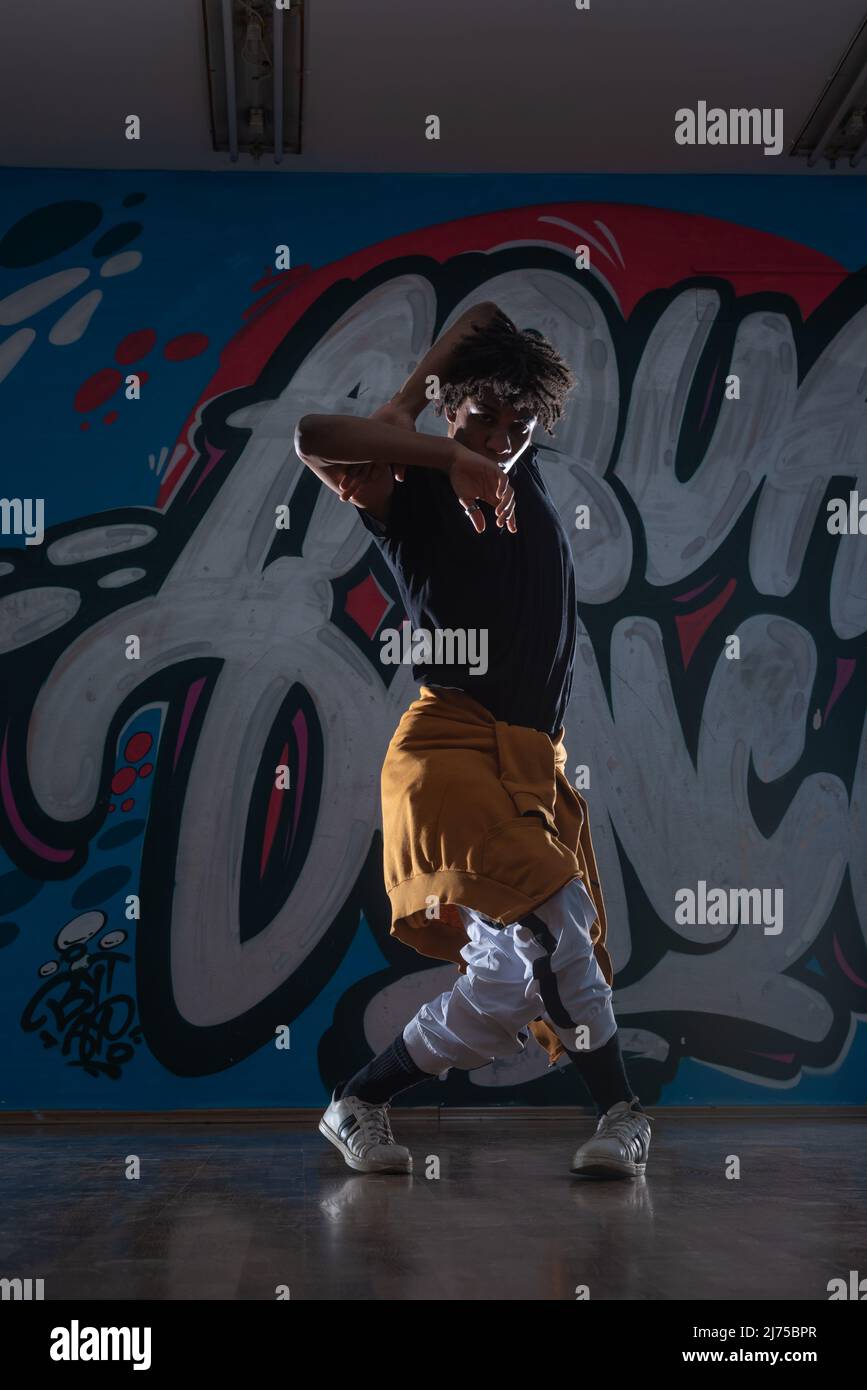 African American hip hop dancer (breakdancer) performing over graffiti ...