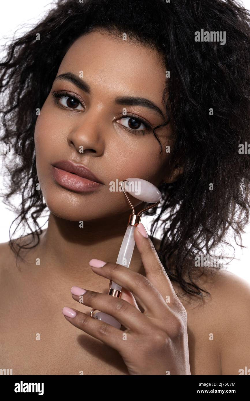 Beautiful black woman with a smooth skin using rose quartz derma roller ...
