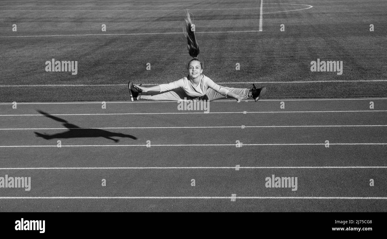 teen girl jumping in split outdoor on racing track stadium, energy ...