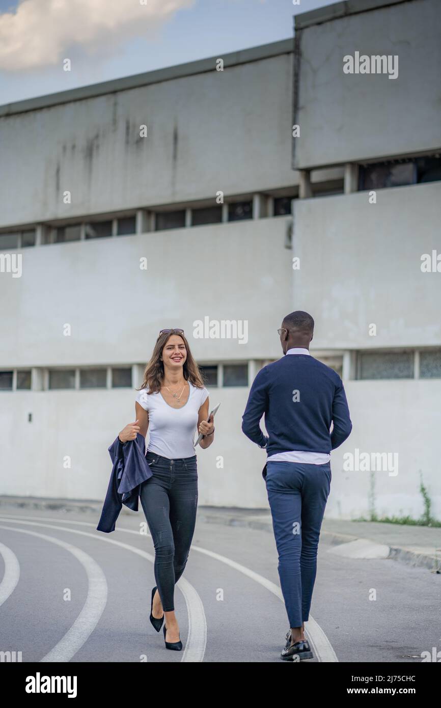 Two multiracial business partners are walking towrds each other while ...