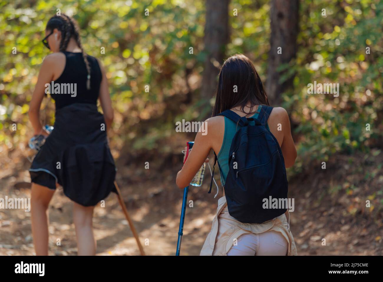 Sisters hiking through beautiful woods while wearing a backpack and ...