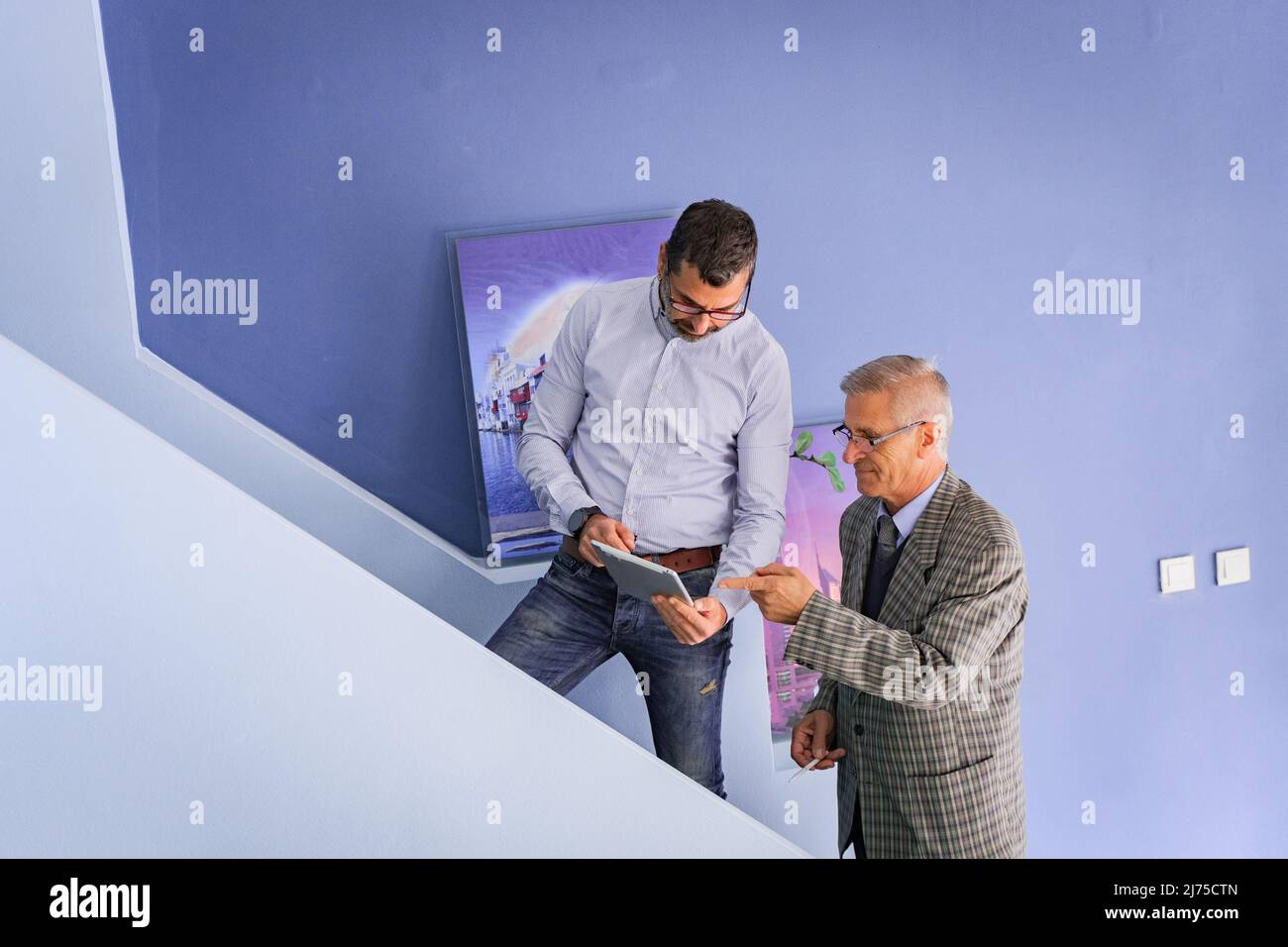 Two senior businessmen are standing on the stairs and looking Stock ...