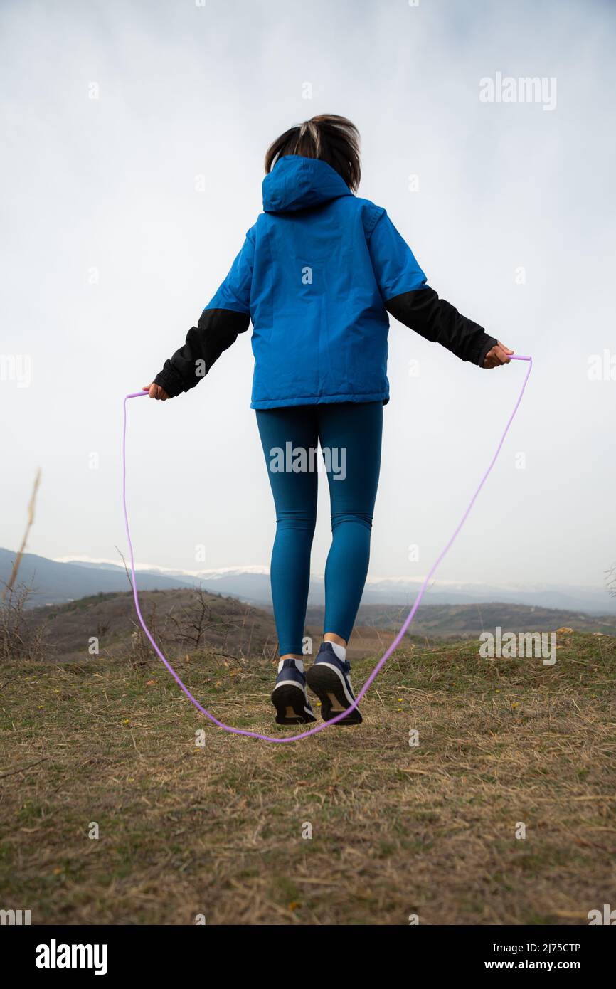 Amazing and active woman is doing a jumping rope exercise in the forest ...