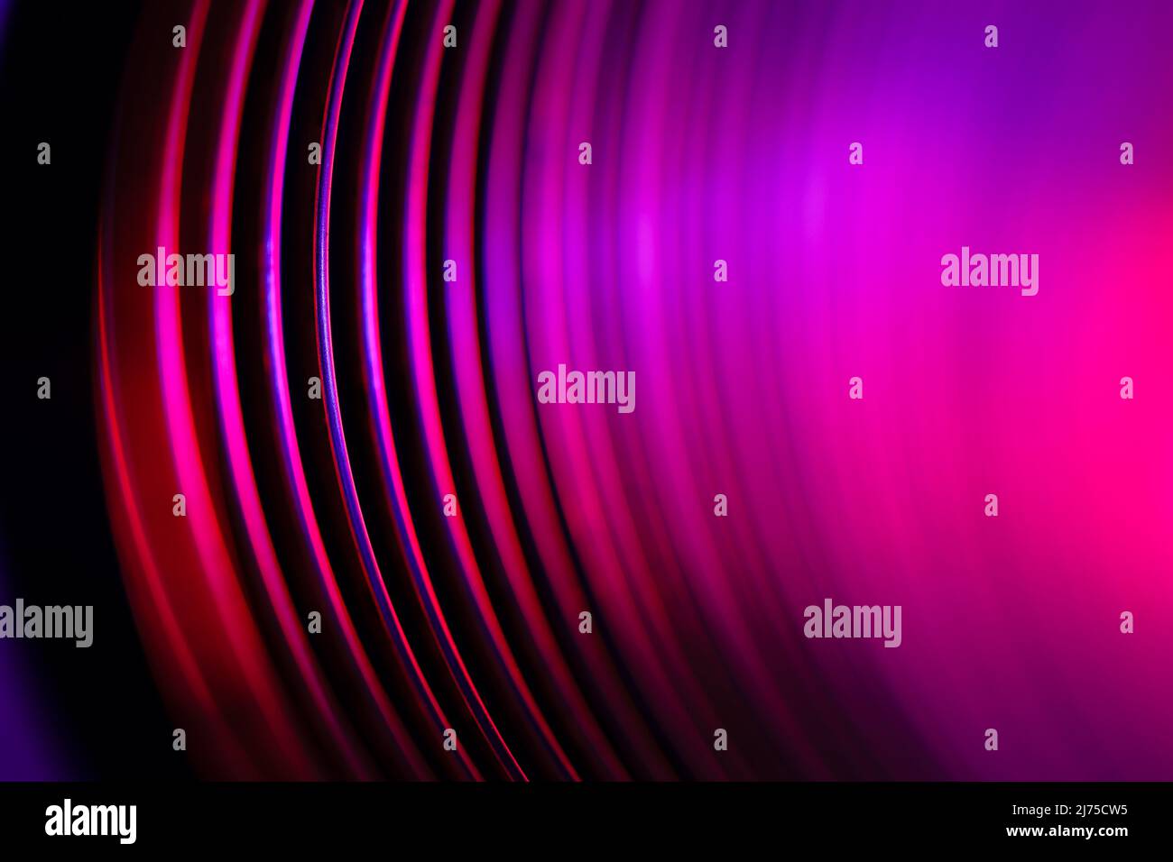 Closeup of coiled metal spring rings in a compressed state in red neon ...