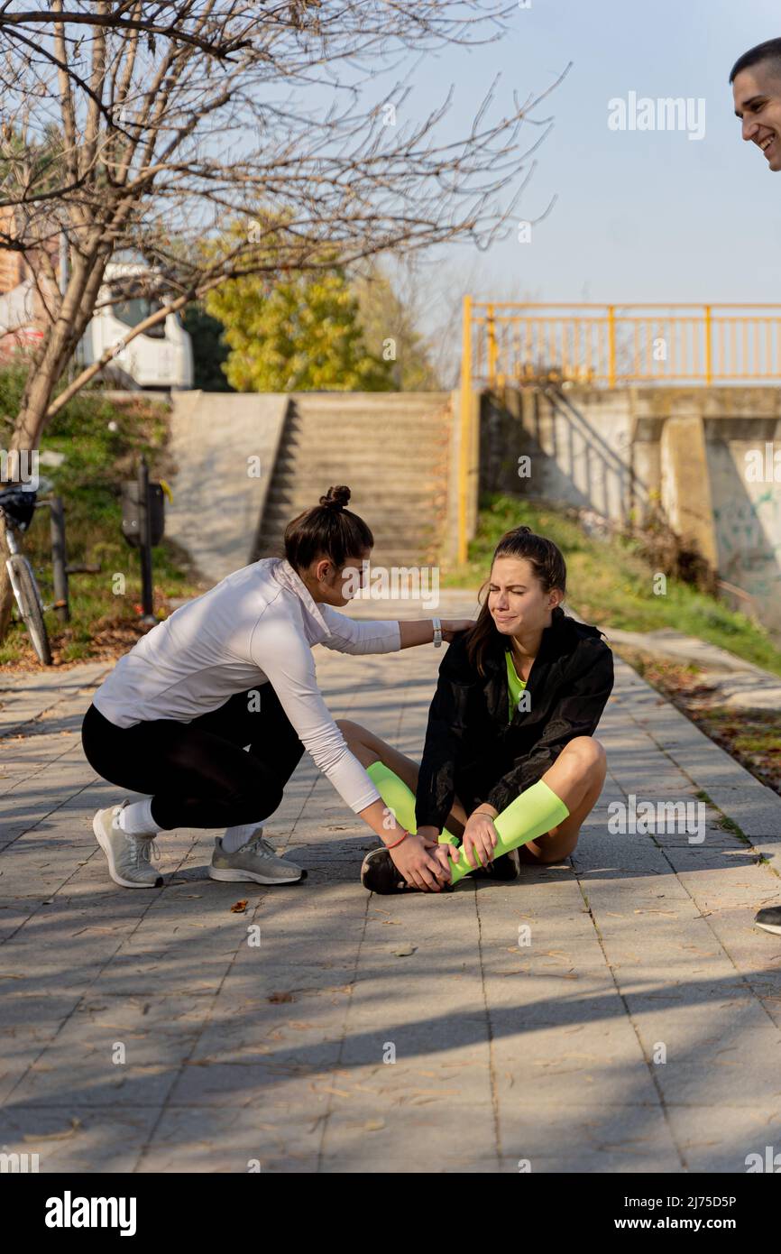 Attractive and beautiful fit girl is sitting while being injured ...