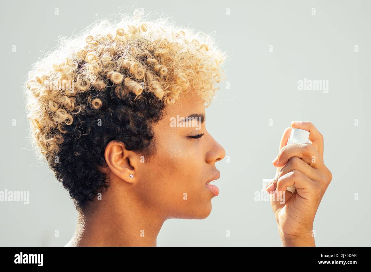 africa american woman using asthma inhaler in the studio white ...