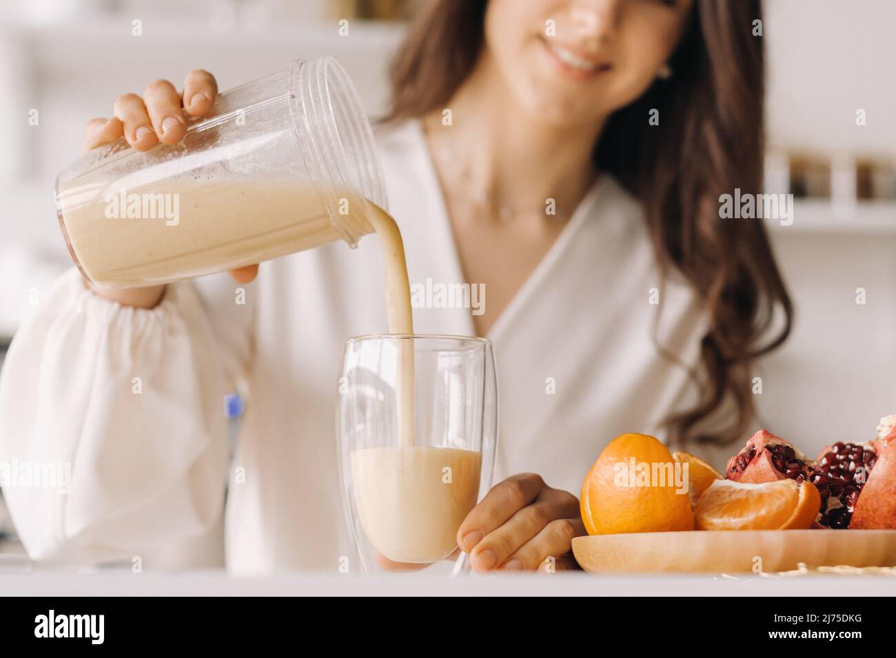 Close-up of a girl's hands pouring a fresh fruit cocktail of bananas ...