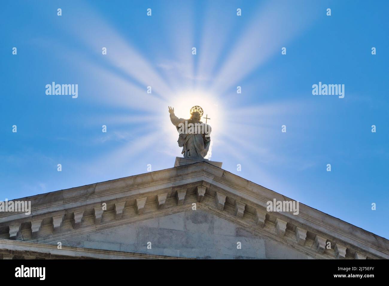 Statue of Jesus Christ surrounded by sun rays against clear blue sky ...