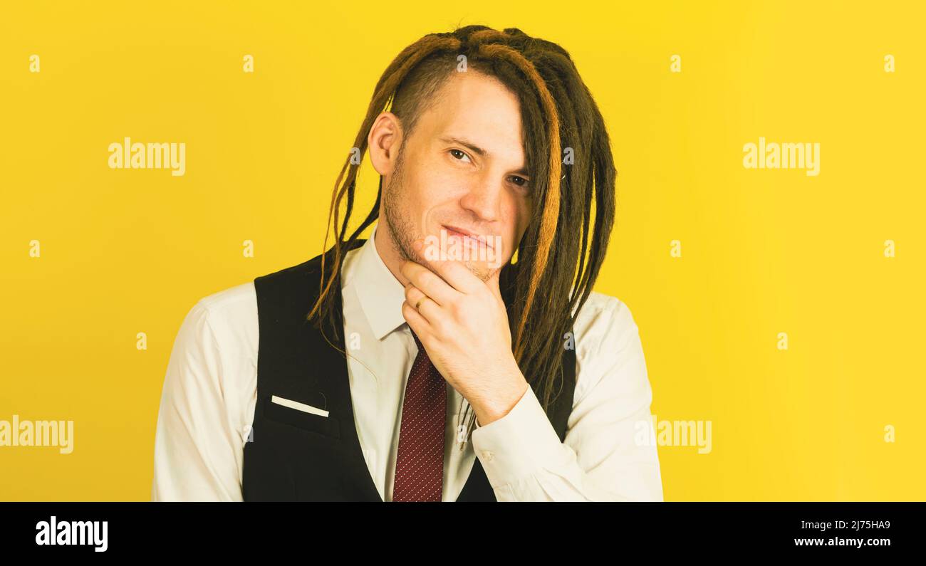 Young happy man looking at camera and scratching chin on yellow ...