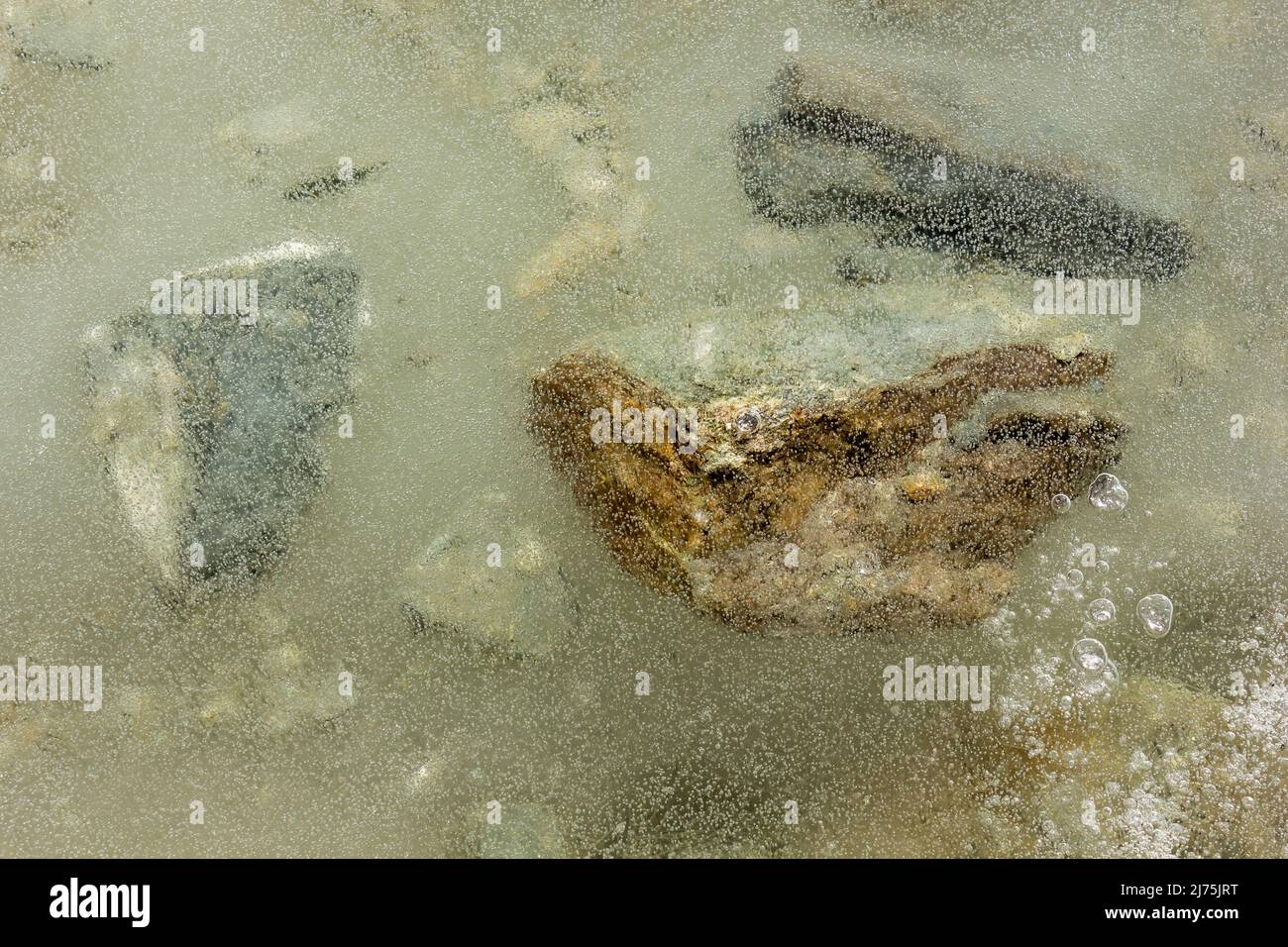Submerged rocks under the surface of a frozen lake near the high ...