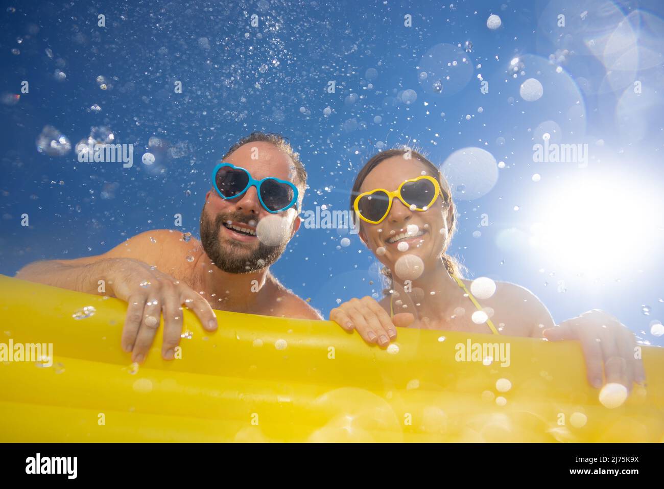 Happy couple having fun on summer vacation. People jumping in swimming ...