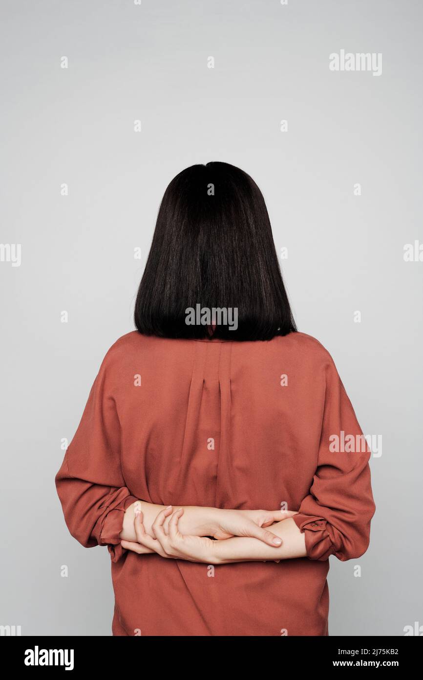 Rear view of unrecognizable brunette woman with tired hands behind back ...