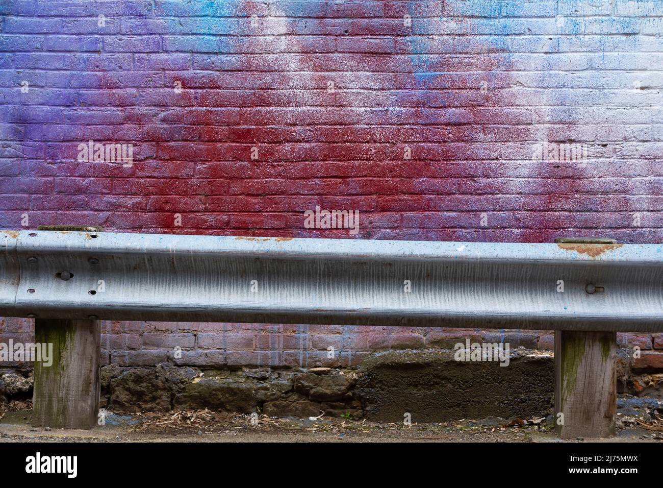 Painted brick wall and metal guard rail in Midwest city back alley ...