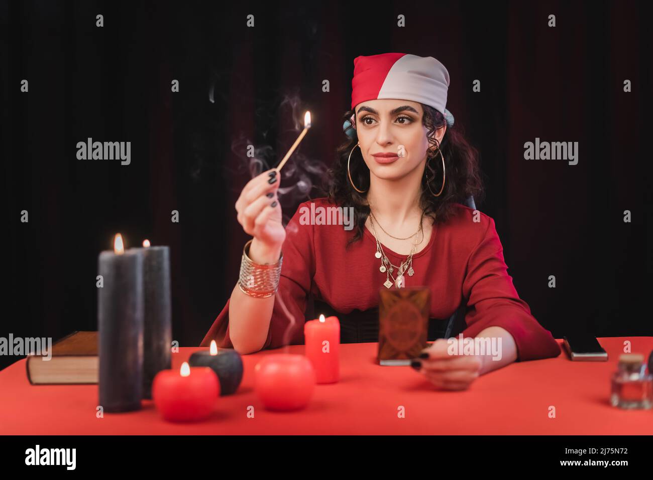 Gypsy fortune teller holding match and blurred tarot card isolated on ...