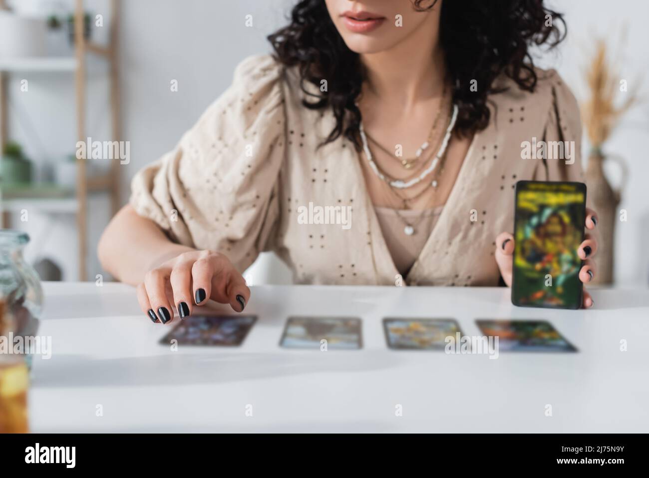 Cropped view of soothsayer holding blurred tarot cards near table Stock ...