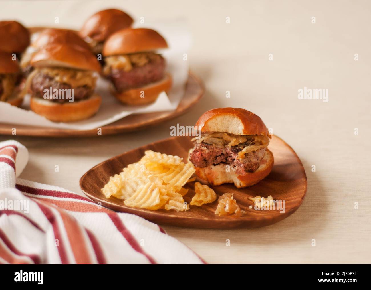 Hamburger Slider with a Bite Taken Out on a Plate with Potato Chips ...
