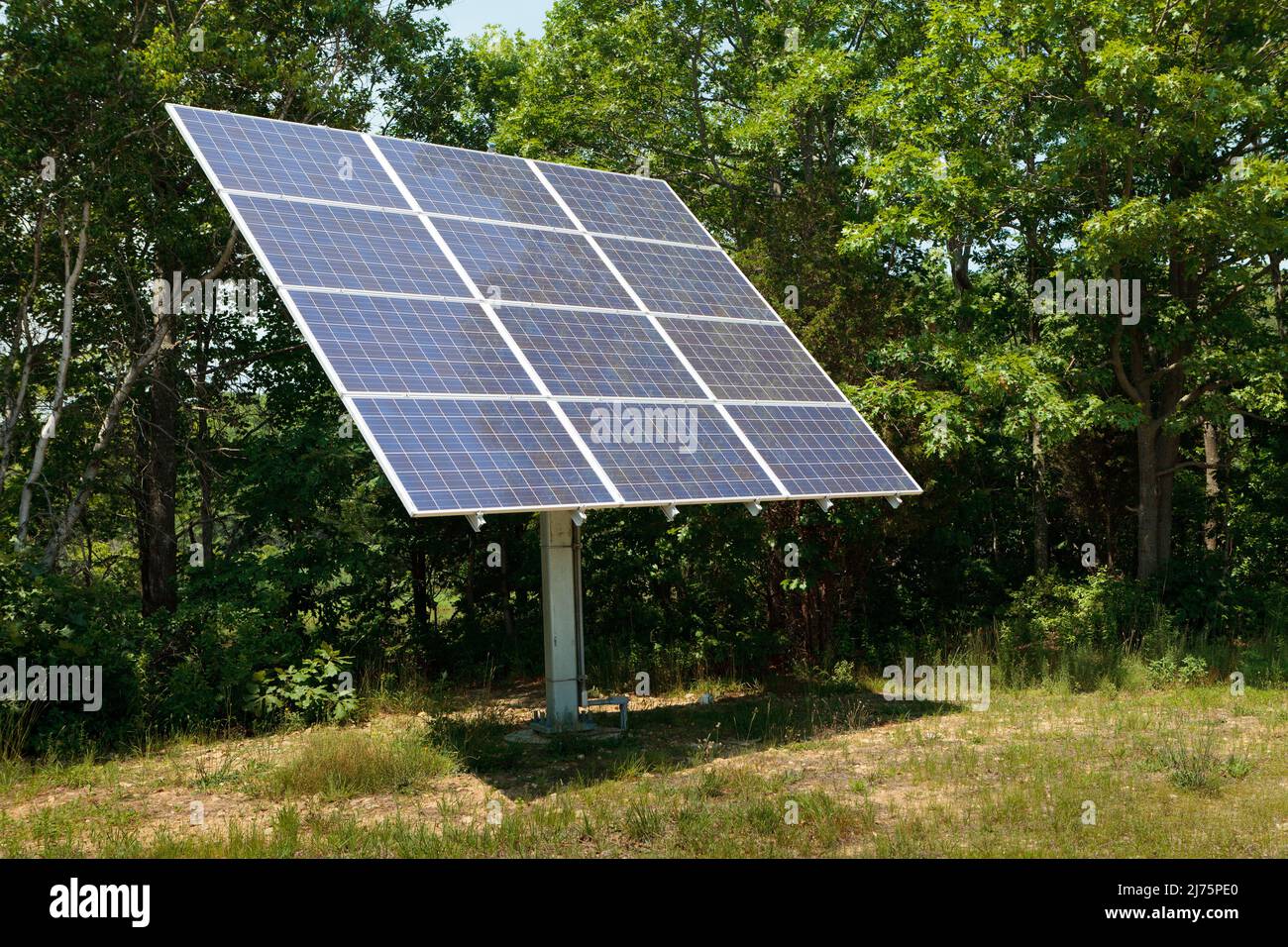 Rotating solar panel in a field set against a wooded area Stock Photo ...