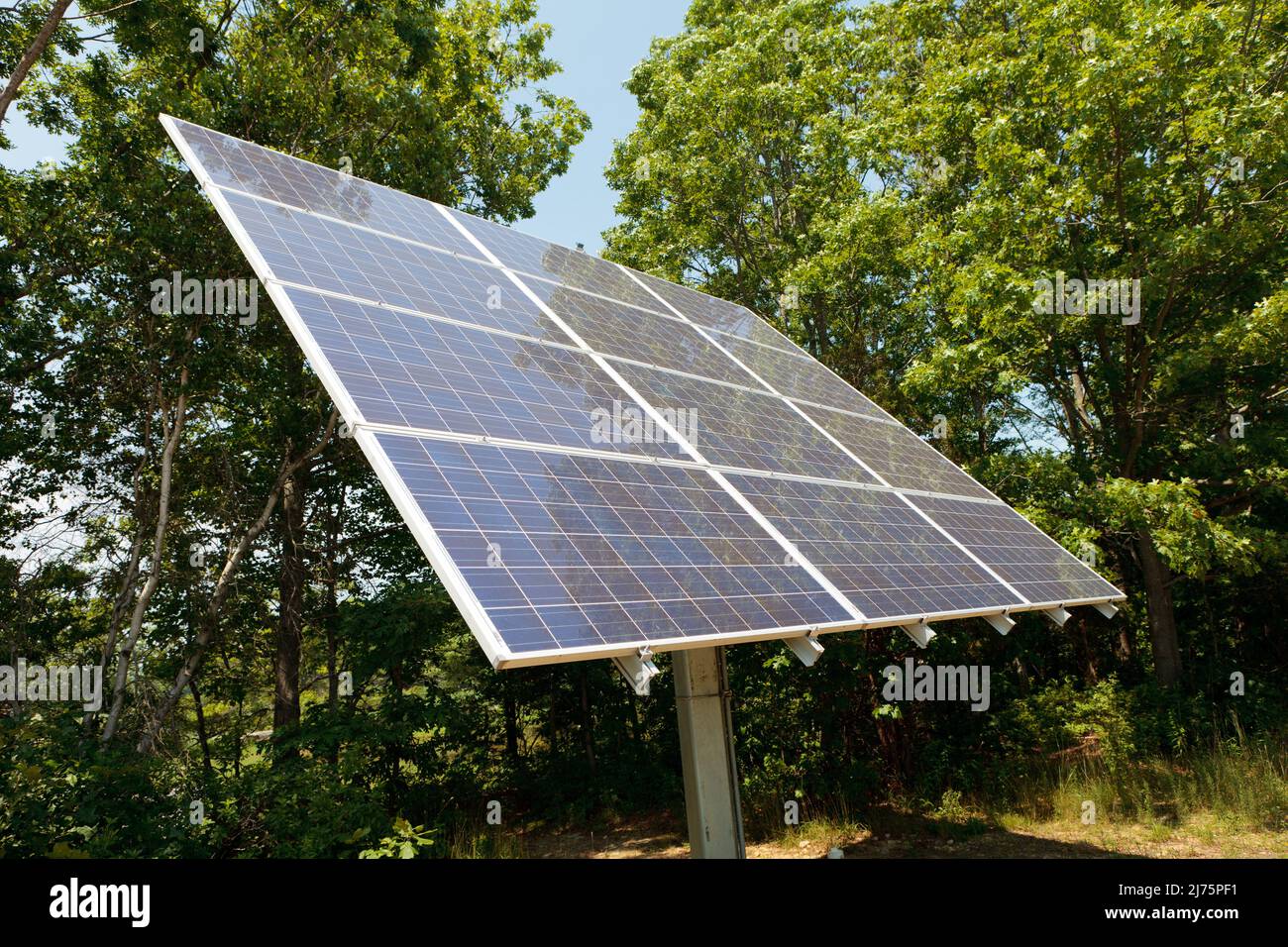 Rotating solar panel in a field set against a wooded area Stock Photo ...