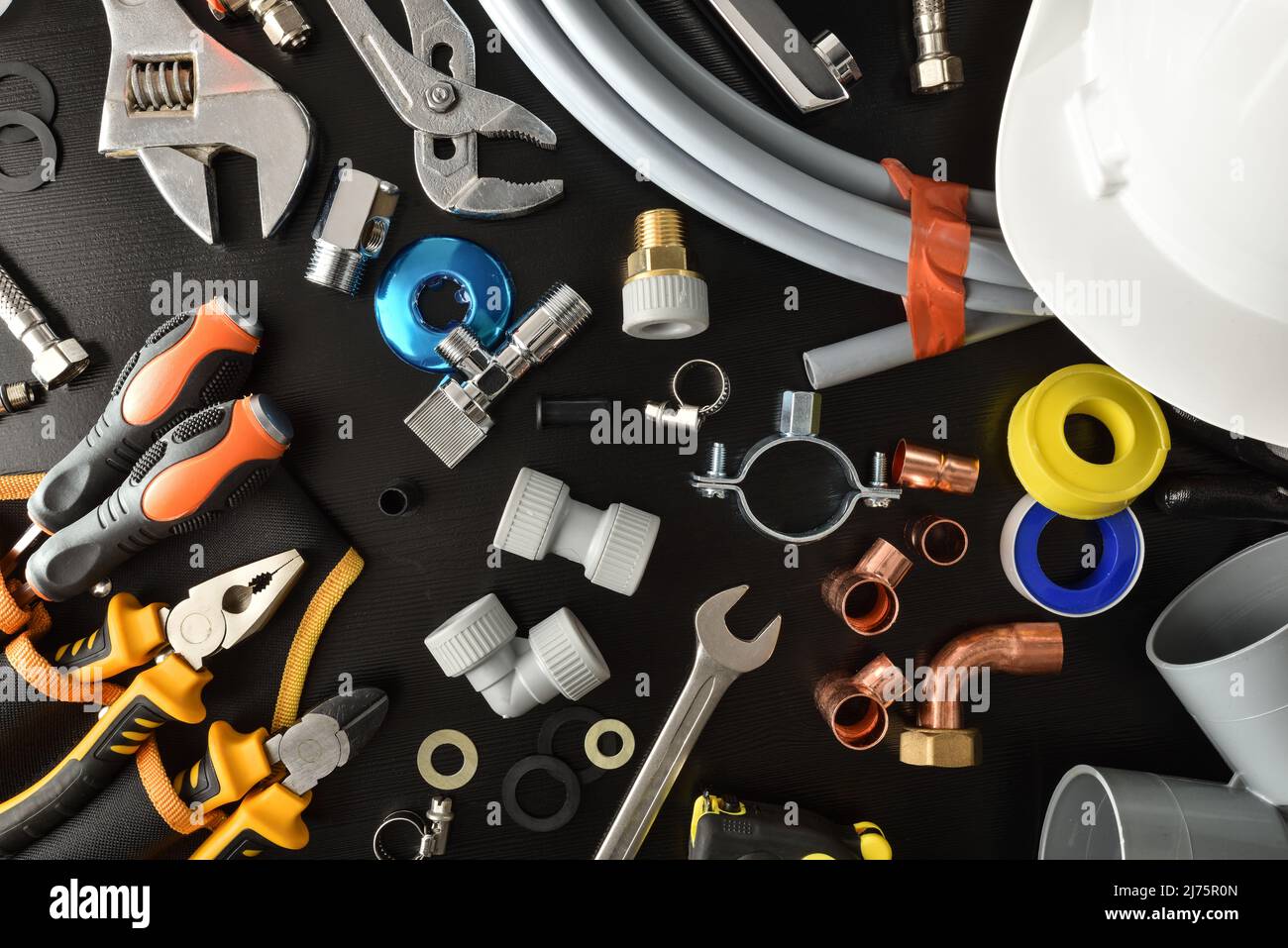 Sample of plumbing materials and tools on black workbench. Top view ...