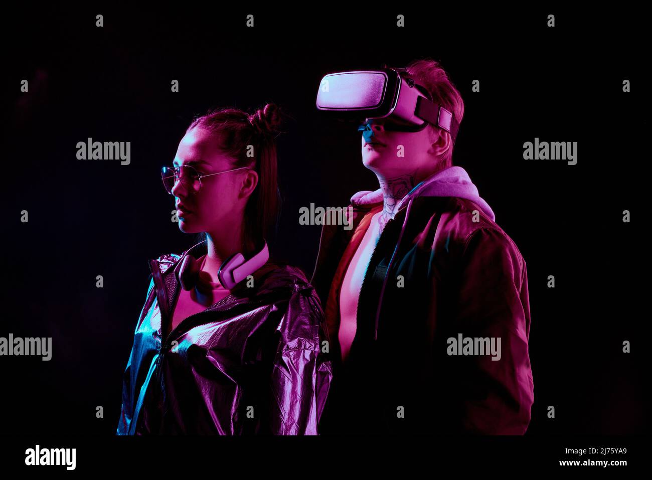 Serious young couple in modern clothes using virtual reality simulator ...