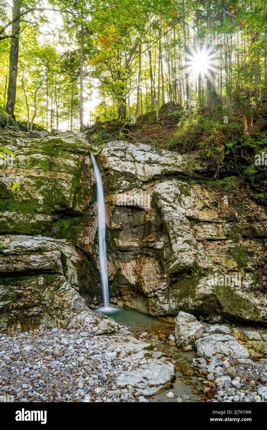 One of the Kesselbach waterfalls with green forest and sun with ...