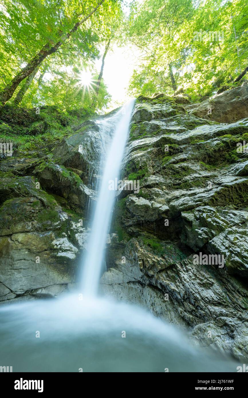 One of the Kesselbach waterfalls with green forest and sun with ...