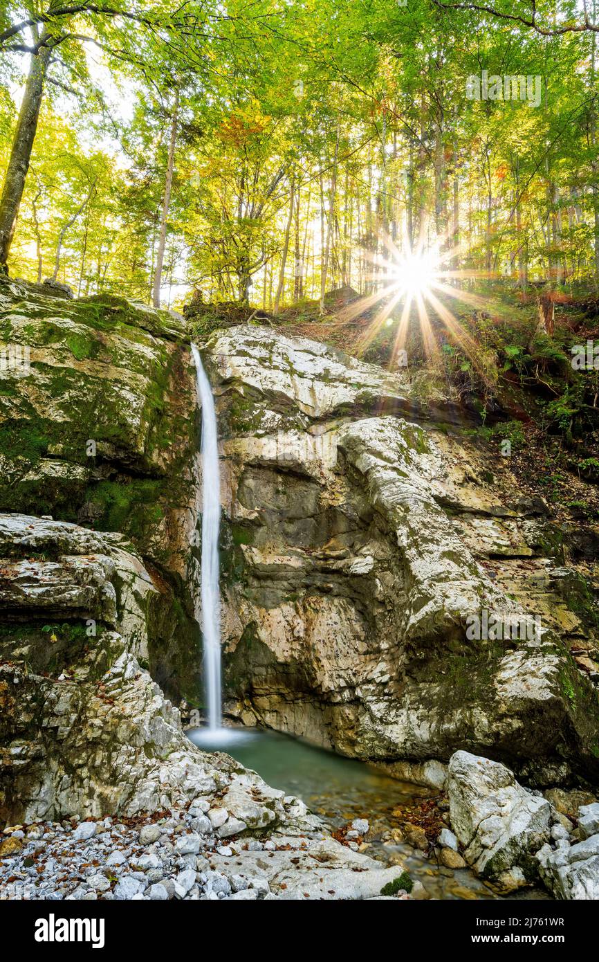 One of the Kesselbach waterfalls with green forest and sun with ...