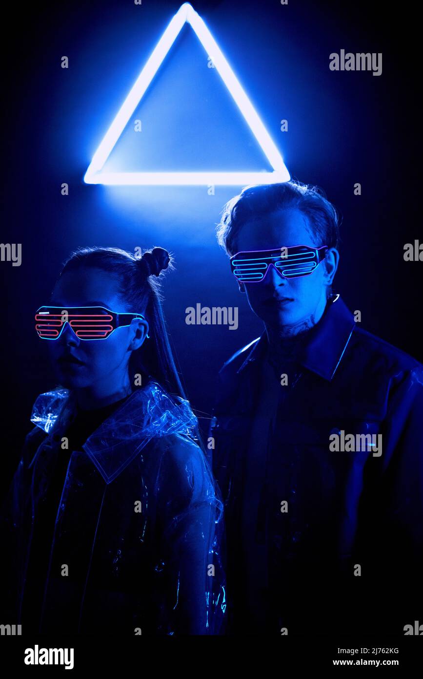 Portrait of serious young cyber people in neon flashing goggles ...