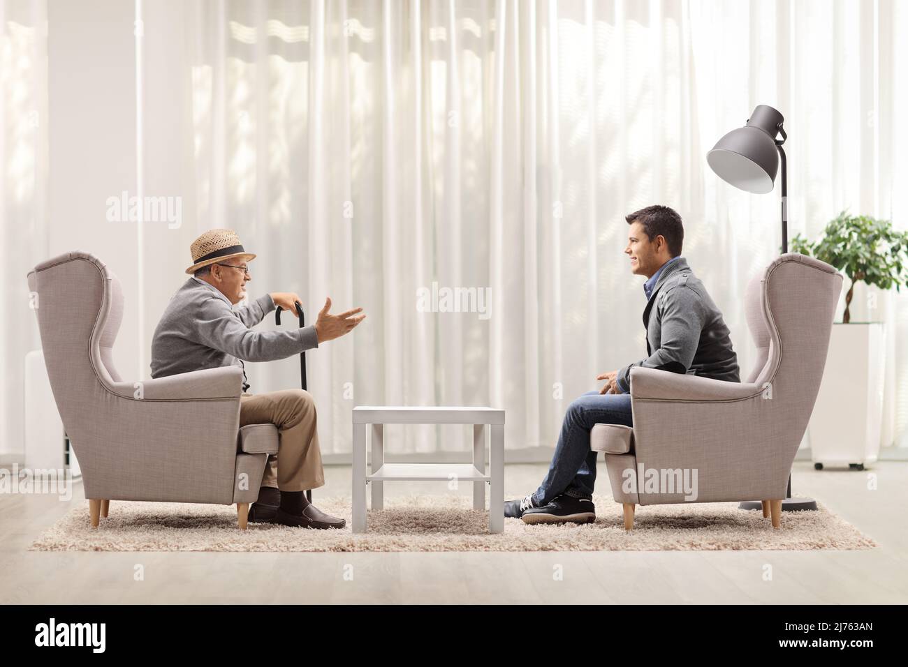 Grandfather and grandson having a conversation at home seated in ...