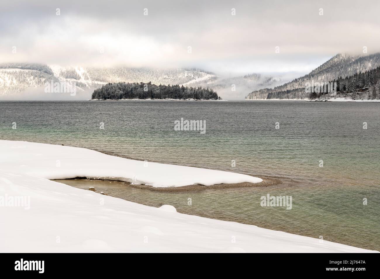 The small island of Sassau in Walchensee in the Byrian Alps covered ...