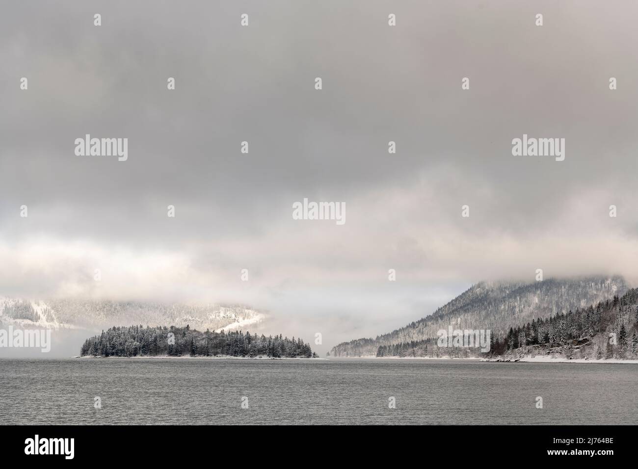 The small island of Sassau in Walchensee in the Byrian Alps covered ...