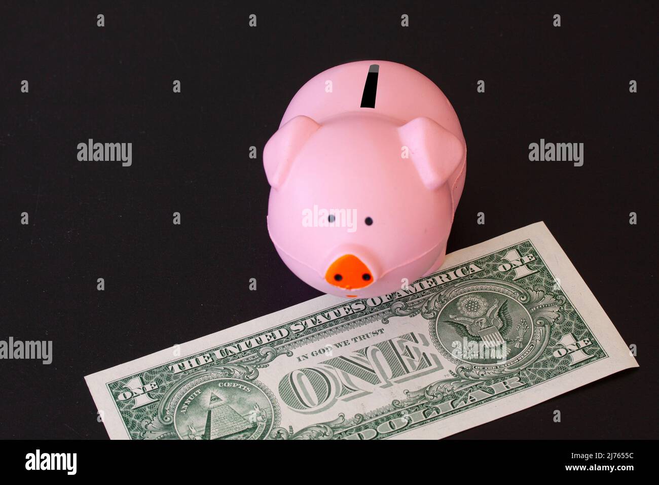 Pink piggy bank standing on a one Dollar banknote. Savings concept ...