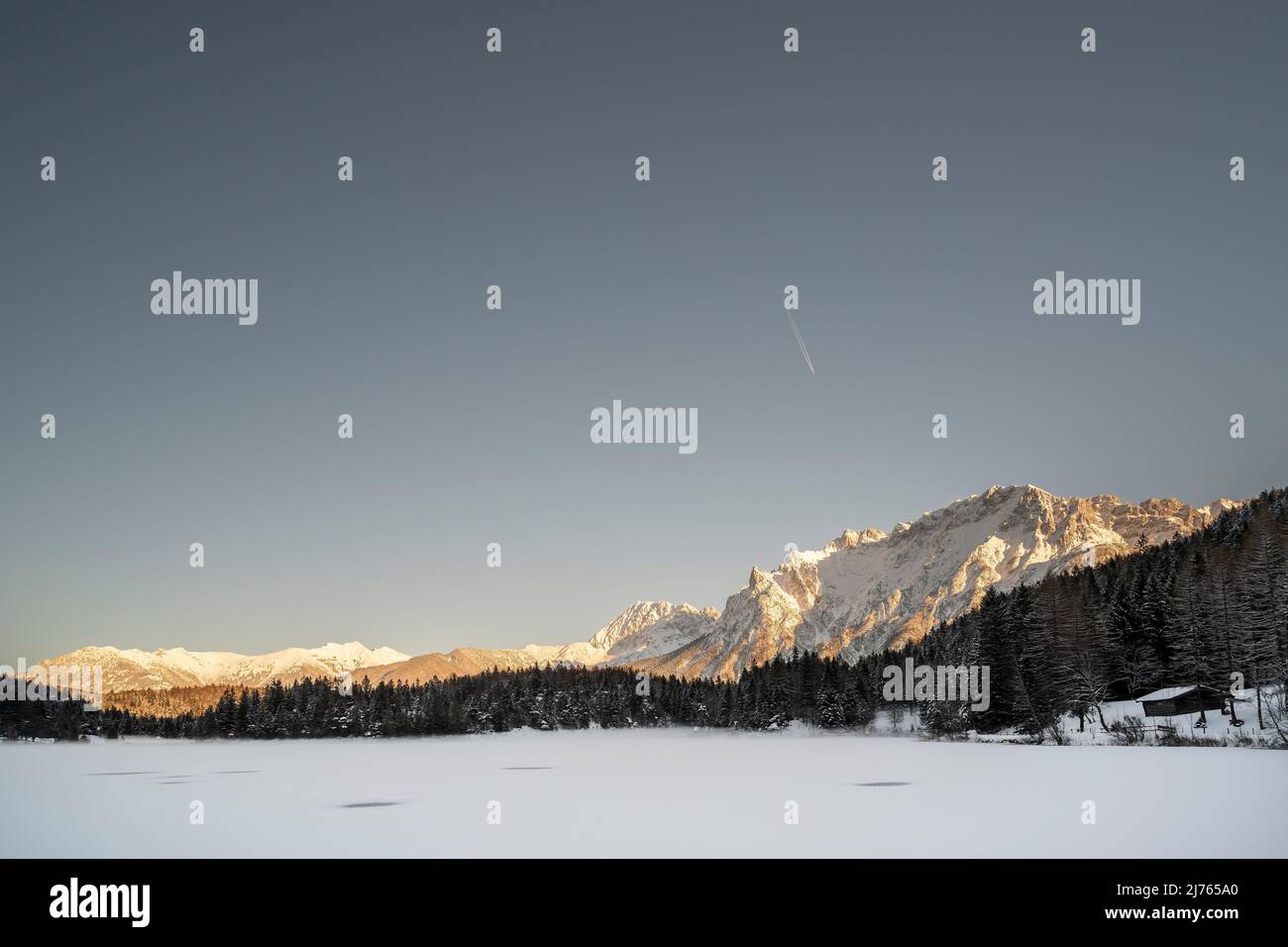 The frozen Lautersee in snow and ice in winter, in the background the ...