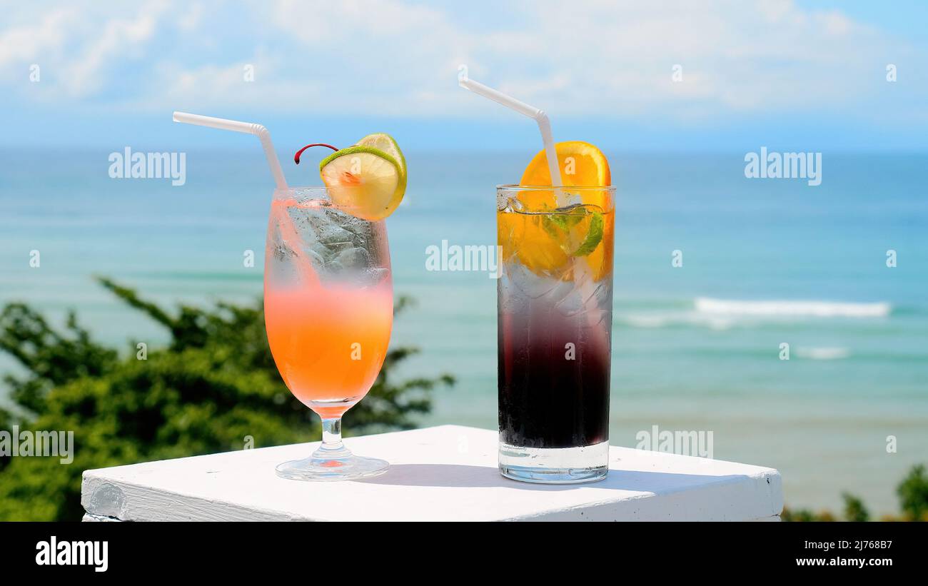 Two tropical fresh iced mocktails on the bar table with sea beach on ...