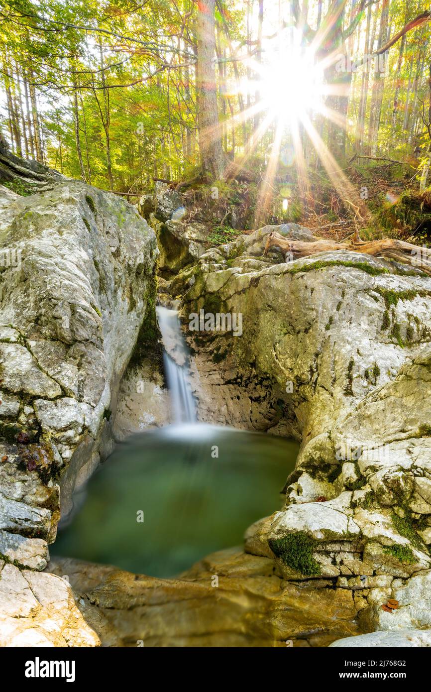 One of the Kesselbach waterfalls with green forest and sun with ...