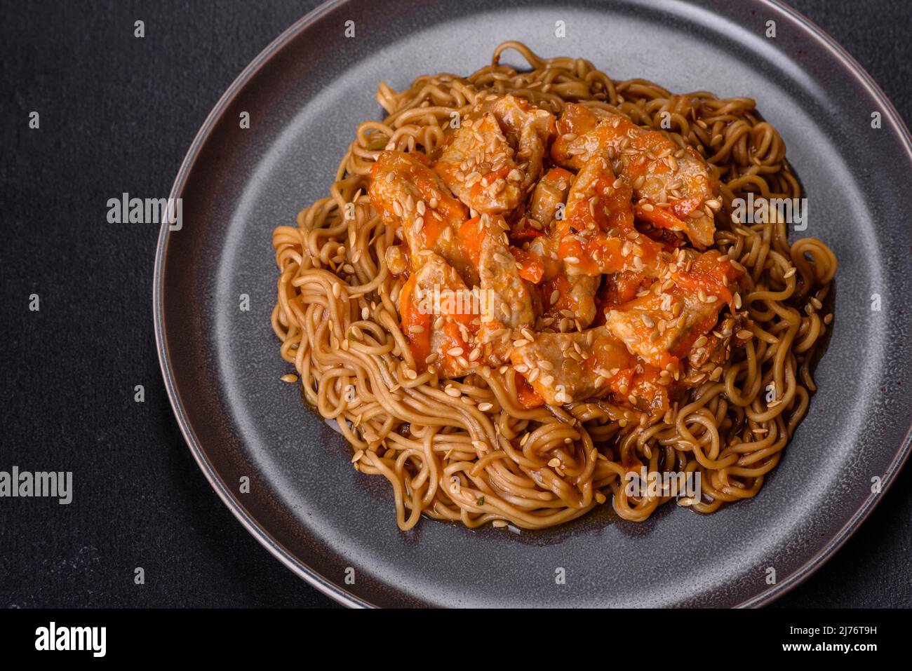Plate of fried noodles and vegetables with hot chicken sauce on ...