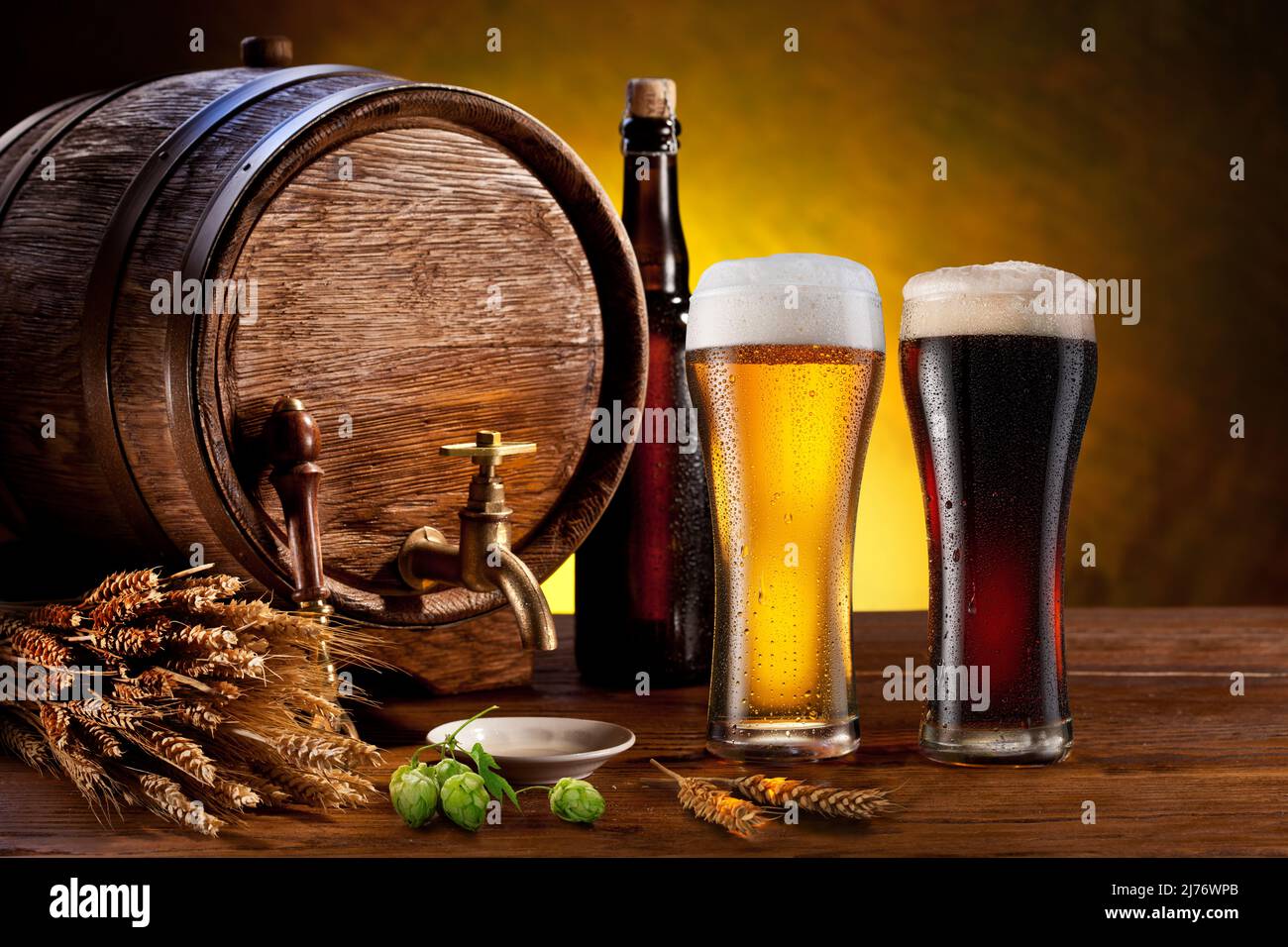 Cooled glasses of three different beer near old wooden cask and dry ...