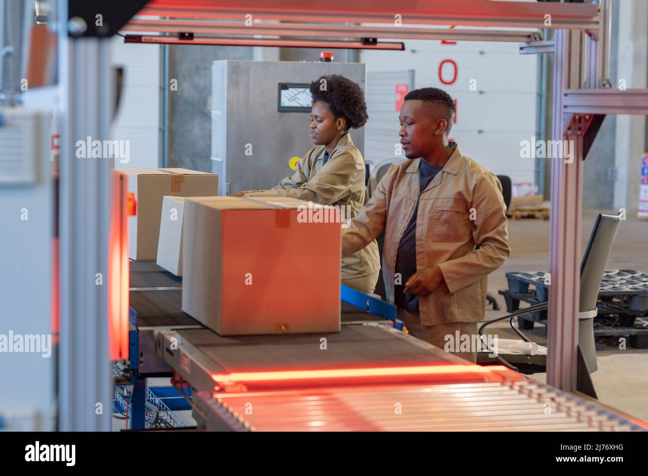 African american young male worker with woman placing cardboard boxes ...