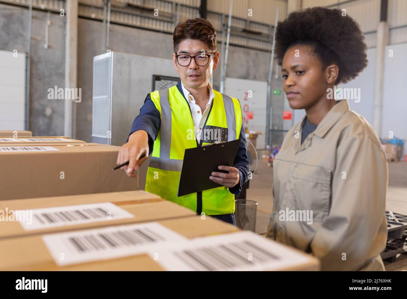 Asian male manager pointing towards cardboard box while guiding african ...