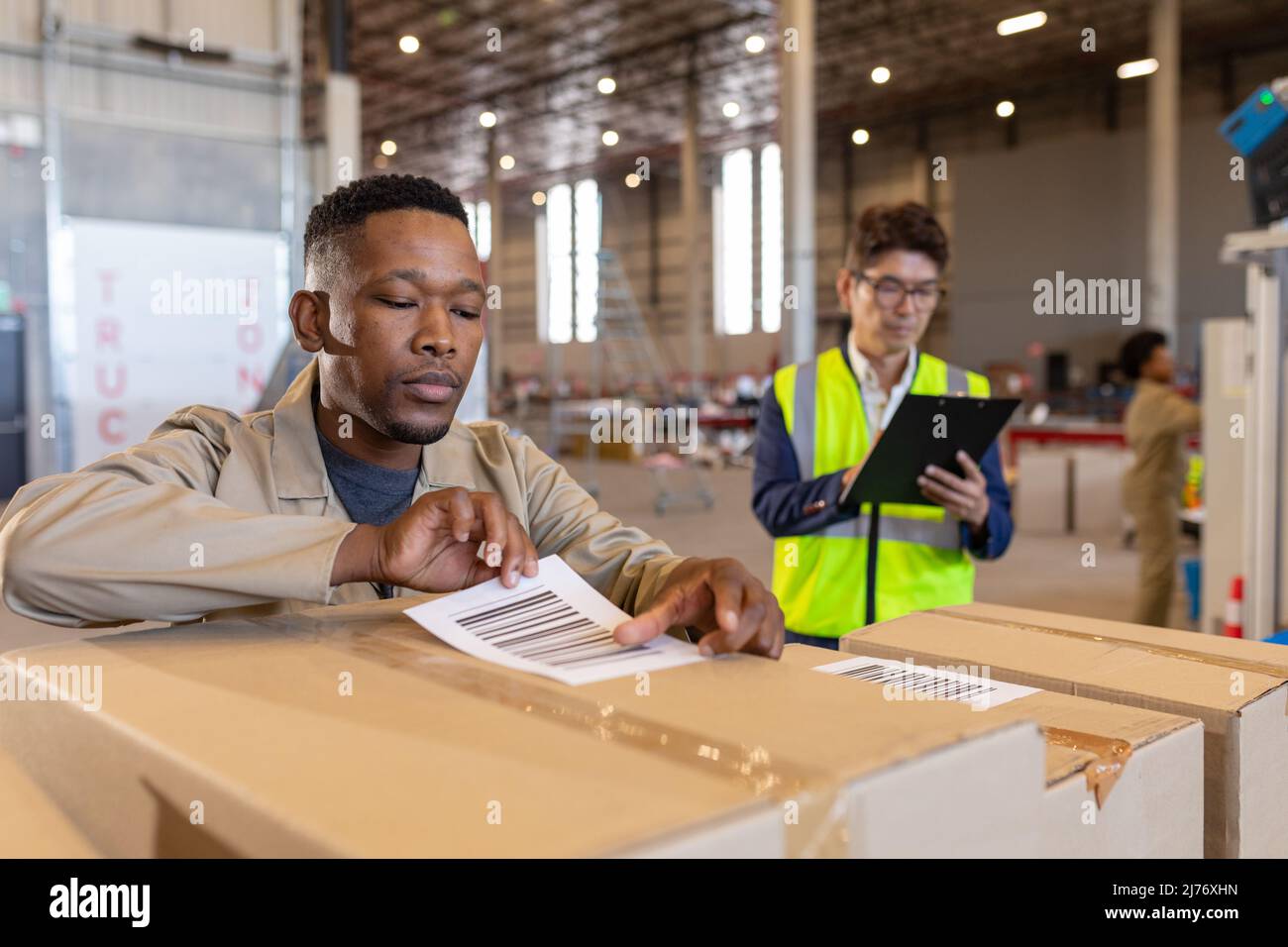African american young man labeling cardboard box with barcode and ...