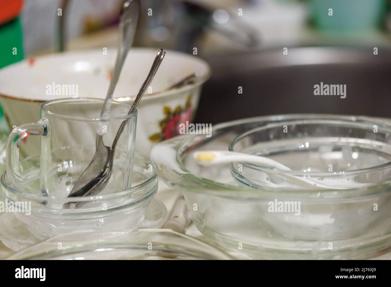 dirty kitchenware partially covered with detergent sud in process of ...