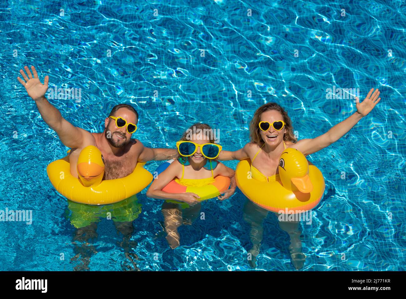 Happy family playing in outdoor pool. People having fun on summer ...