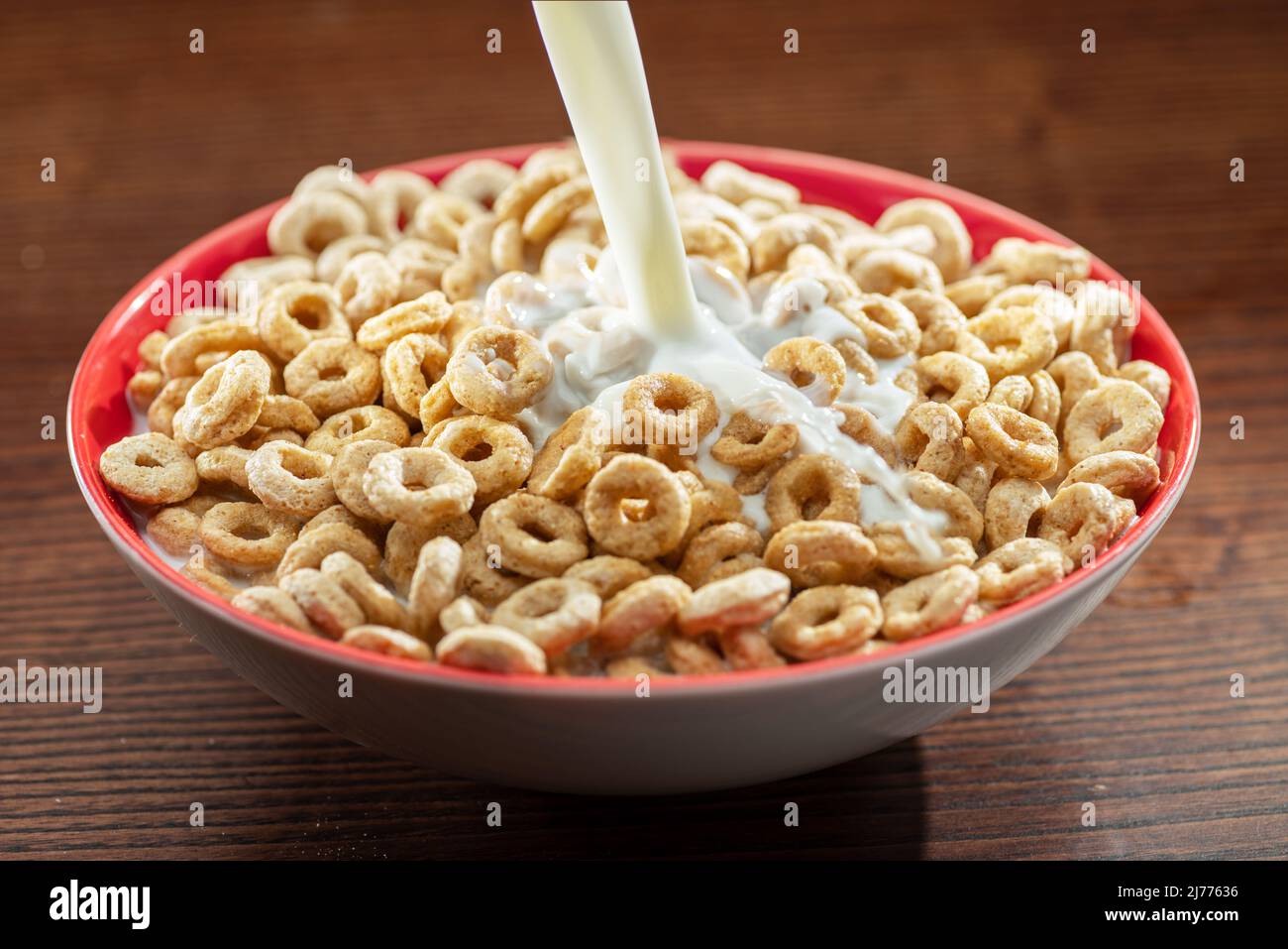 Pouring milk into the bowl with corn snacks. Close-up Stock Photo - Alamy
