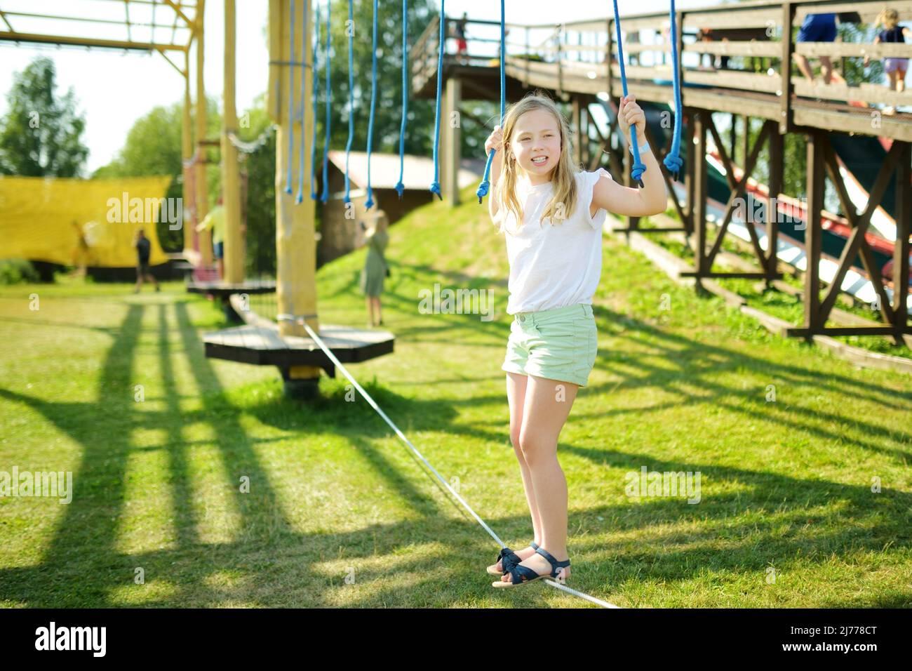 Adorable little girl having a good time climbing in adventure park ...