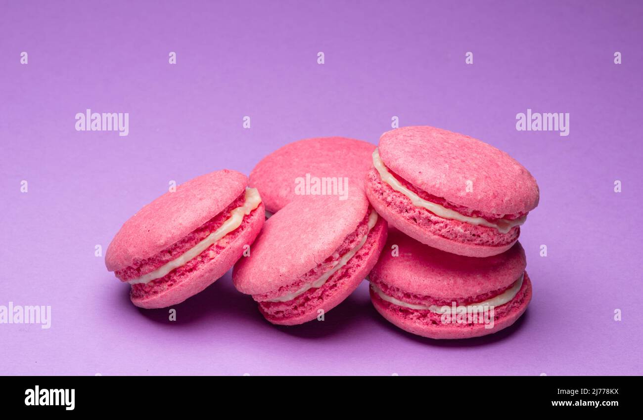 Colorful sweet macarons or macaroons, flavored cookies on purple ...