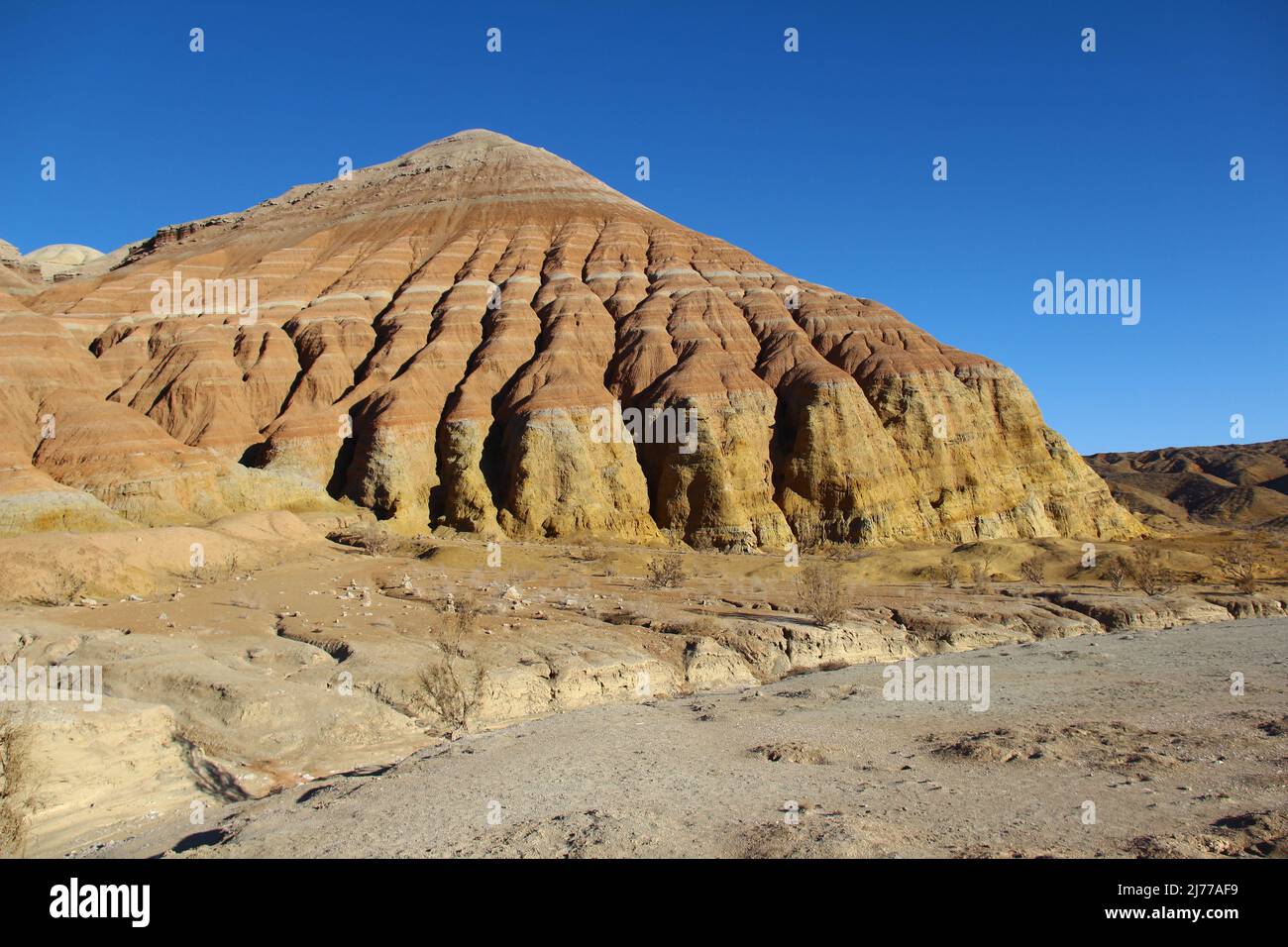 A huge sandy-clay multi-colored mountain with relief slopes in the ...
