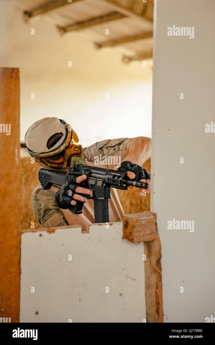 Man in camouflage suit aiming a gun in an airsoft match Stock Photo - Alamy